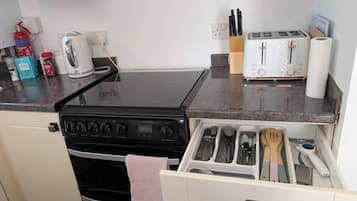 Uma cozinha com fogão, torradeira e gaveta com utensílios.