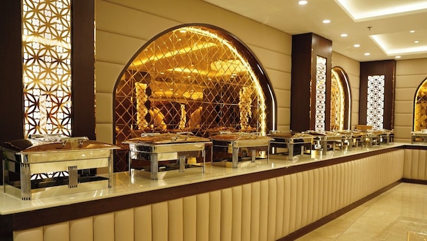 Uma área de buffet com várias estações de serviço, parede estampada e iluminação acolhedora.