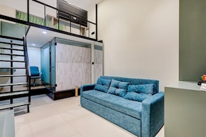 Uma sala de estar moderna com um sofá azul, uma divisória de vidro e uma escada preta.
