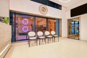 Decoração moderna com balcão de atendimento, relógio e área de estar com cadeiras.