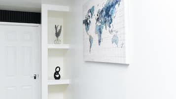 Quarto com porta branca, um mapa-múndi na parede e uma estante com objetos decorativos.