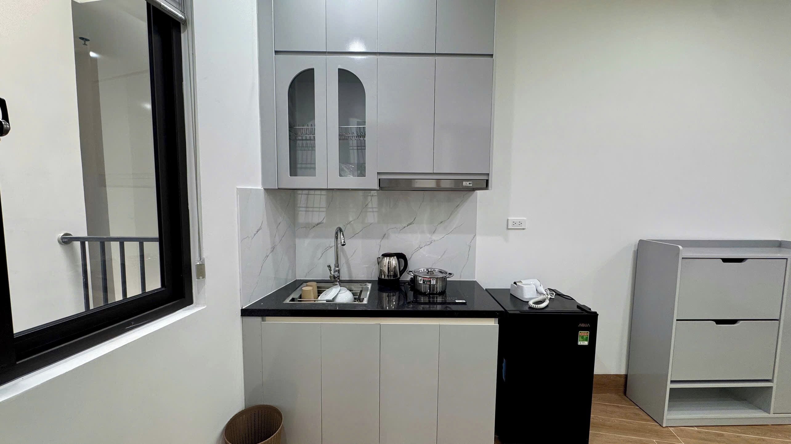 Uma cozinha compacta com pia, chaleira e pequeno frigorífico.