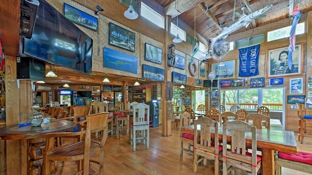 Um restaurante com mobiliário de madeira, uma televisão grande e várias decorações nas paredes.