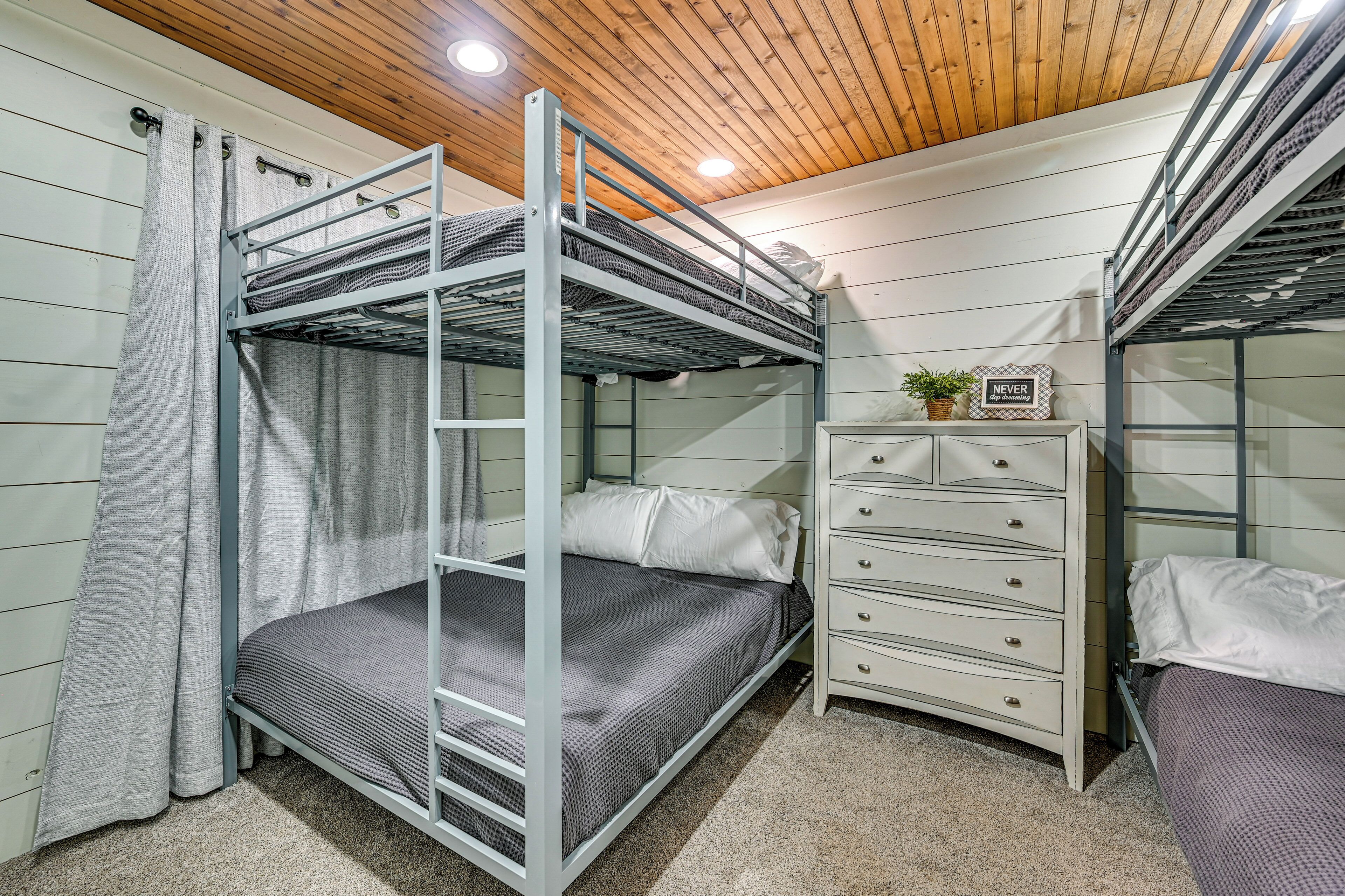 Quarto com beliche, cômoda com gavetas e prateleira na parede com uma planta.