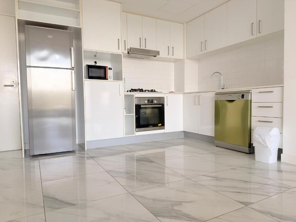 Cozinha moderna com geladeira de aço inoxidável, micro-ondas, forno e lava-louças.