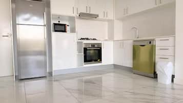 Cozinha moderna com geladeira de aço inoxidável, micro-ondas, forno e lava-louças.