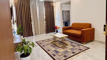 Uma sala de estar moderna com um sofá, uma mesa de centro, um tapete estampado e um vaso com planta.