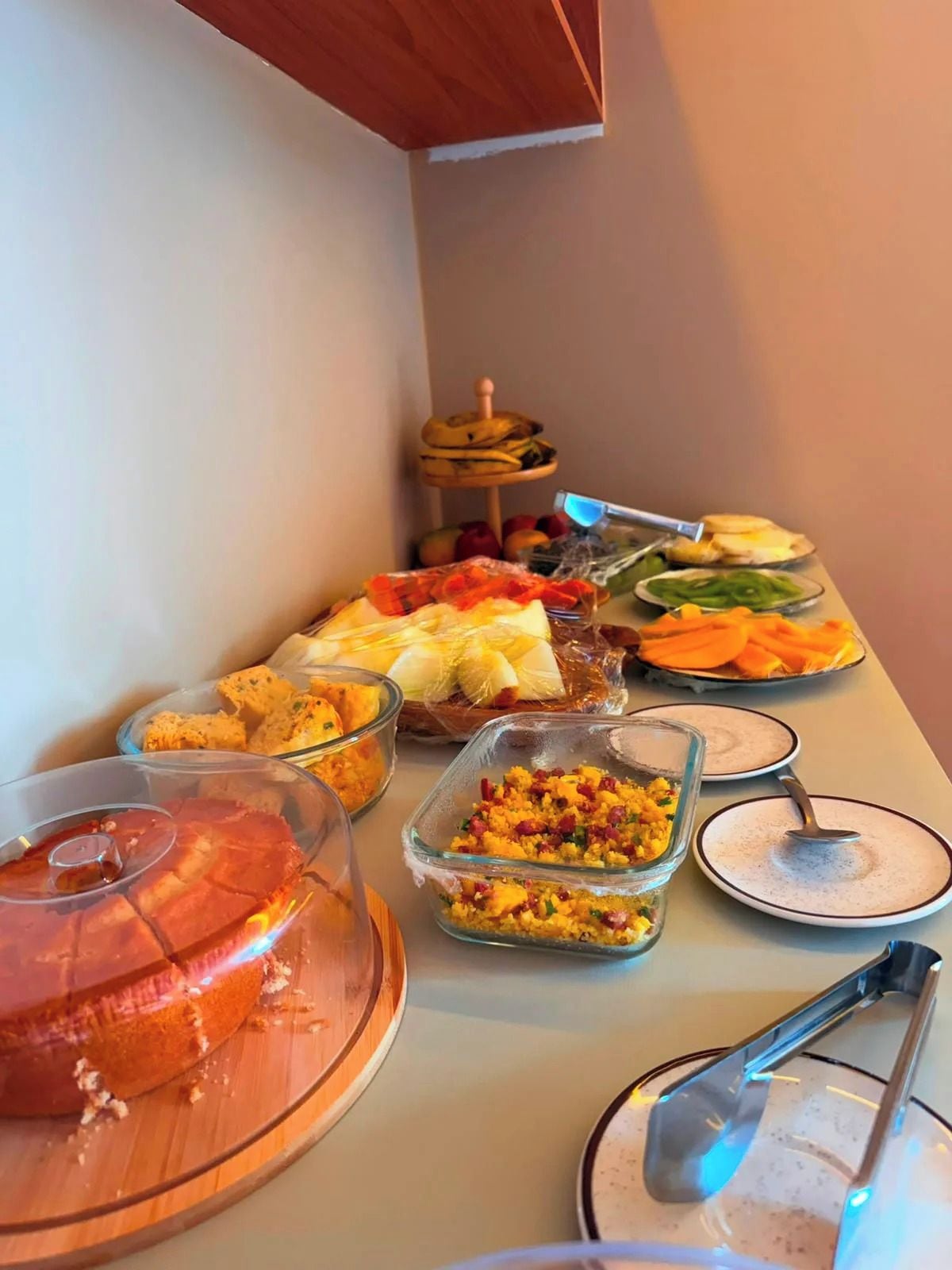 Mesa de buffet com diversos alimentos, incluindo frutas, legumes e pratos preparados.