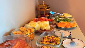 Mesa de buffet com diversos alimentos, incluindo frutas, legumes e pratos preparados.