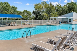 A swimming pool with lounge chairs and a covered seating area.