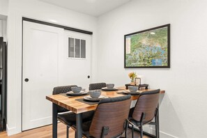 Uma área de refeições com uma mesa de madeira, cadeiras estofadas pretas e um mapa emoldurado na parede.