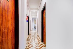 Um corredor com portas de madeira, um chão estampado e um extintor fixado na parede.