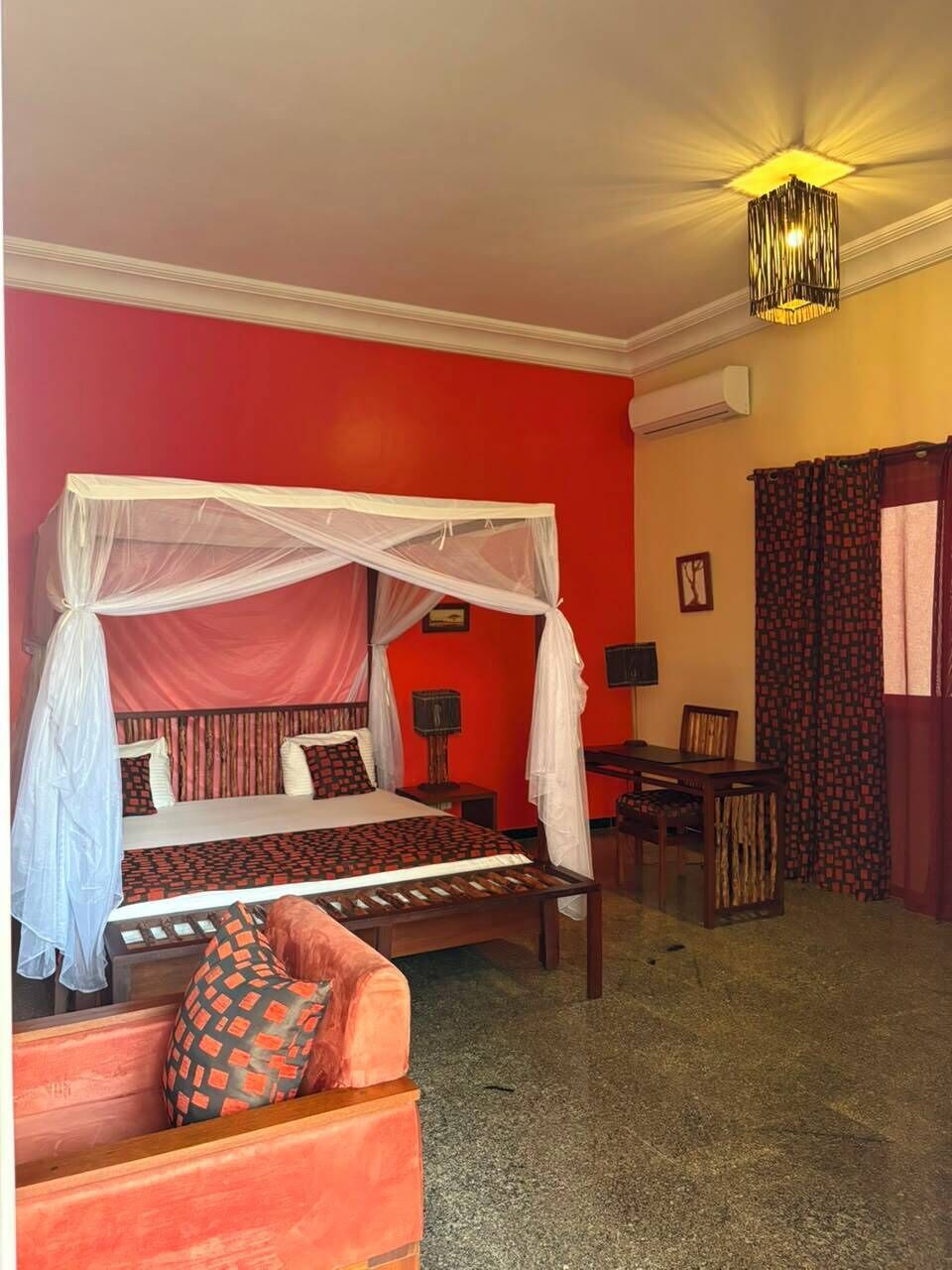 Quarto com uma cama de dossel, uma escrivaninha, uma cadeira e um sofá.