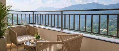 Varanda com mobiliário de vime, uma mesa com vela e vista para montanhas.