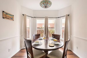 Uma sala de jantar com uma mesa redonda, quatro cadeiras e um candelabro.