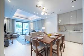 Uma sala de jantar moderna com mesa e cadeiras de madeira, um sofá e vista para o exterior.