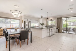 Uma cozinha moderna com ilha central, área de refeições com cadeiras e grandes janelas.