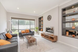Uma sala de estar moderna com sofá, mesa de centro, TV e estantes embutidas.