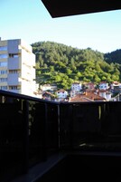 Uma varanda com vista para uma área residencial e uma colina arborizada.