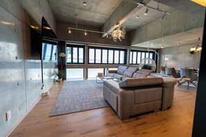 Uma sala de estar moderna com um sofá seccional, uma mesa de centro e um candelabro.