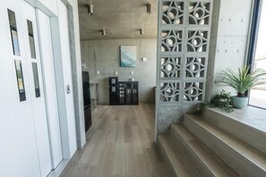 Um interior moderno com piso de madeira, escada, divisória decorativa e um vaso com planta.