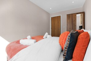 Quarto de hotel com cama, almofadas, porta de madeira e espelho.