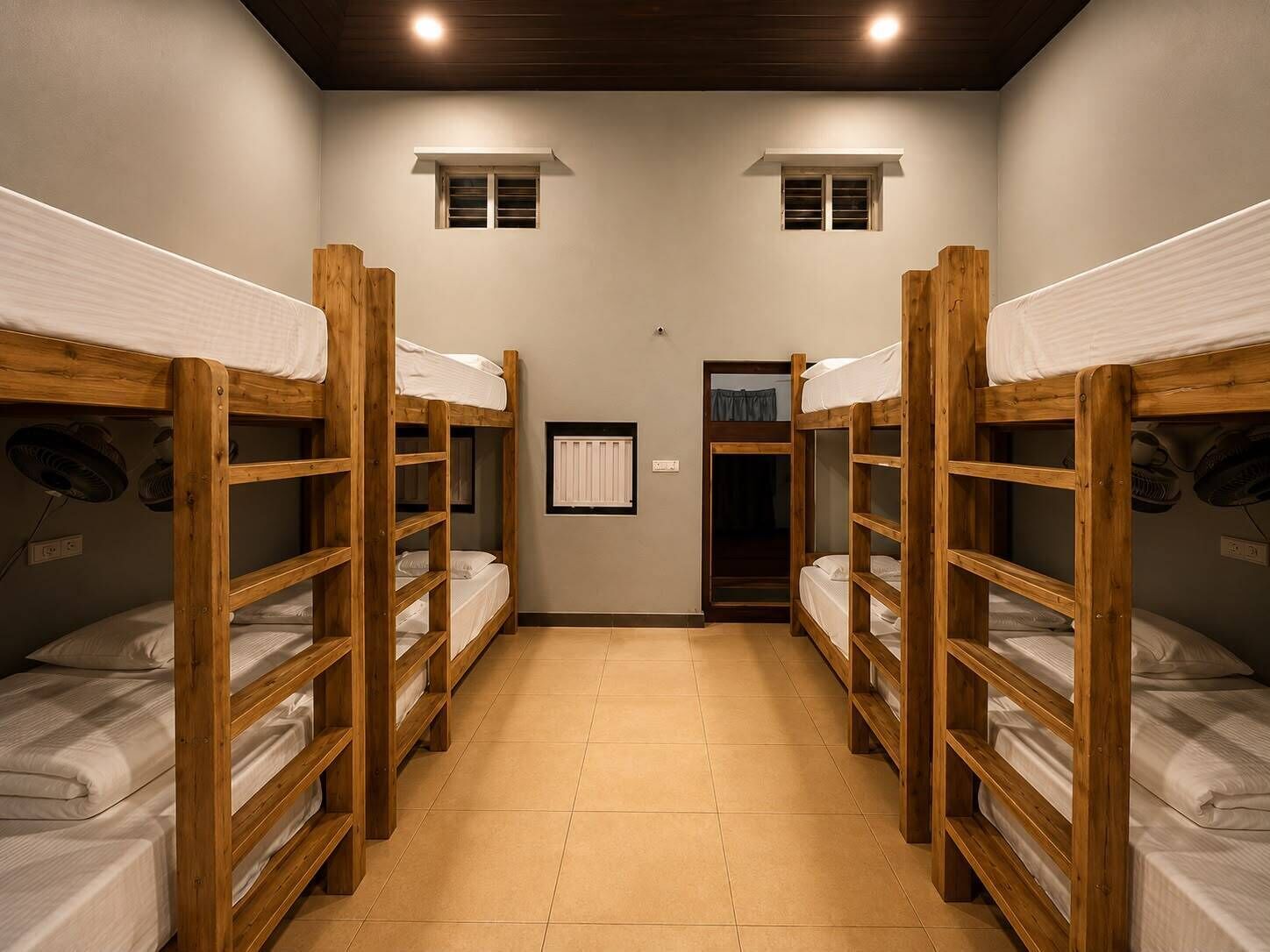 Quarto com beliches, uma porta e uma janela pequena.