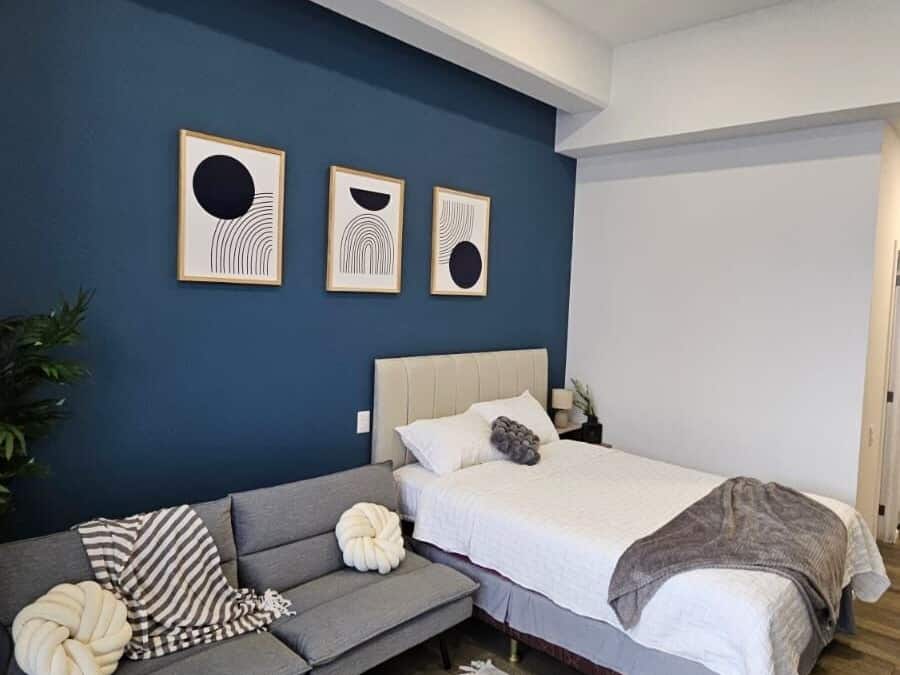 Quarto moderno com cama, sofá e uma mesinha de cabeceira.