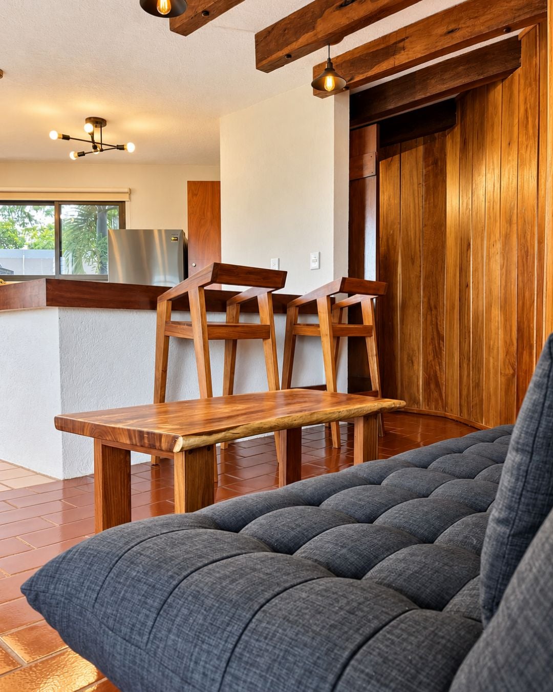 Um interior moderno com uma mesa de jantar de madeira, cadeiras e um sofá cinzento.