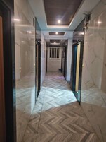 Um corredor com piso em padrão herringbone, portas de vidro e teto com iluminação embutida.