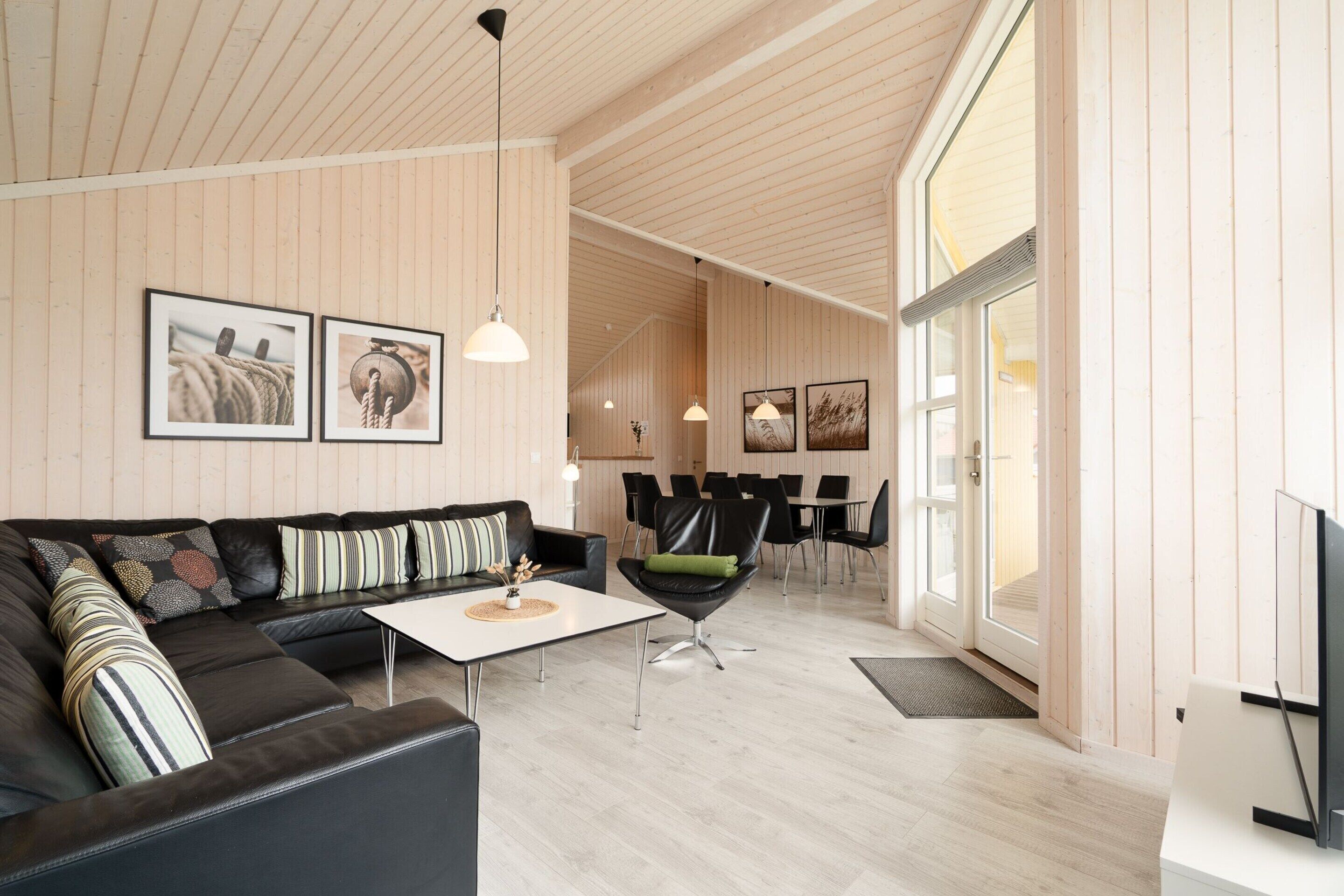 Uma sala moderna com um sofá seccional, uma mesa de centro e um espaço de refeições com cadeiras e uma mesa.