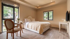 Quarto com uma cama grande, uma escrivaninha e uma cadeira. Há uma janela que oferece vista para o exterior.