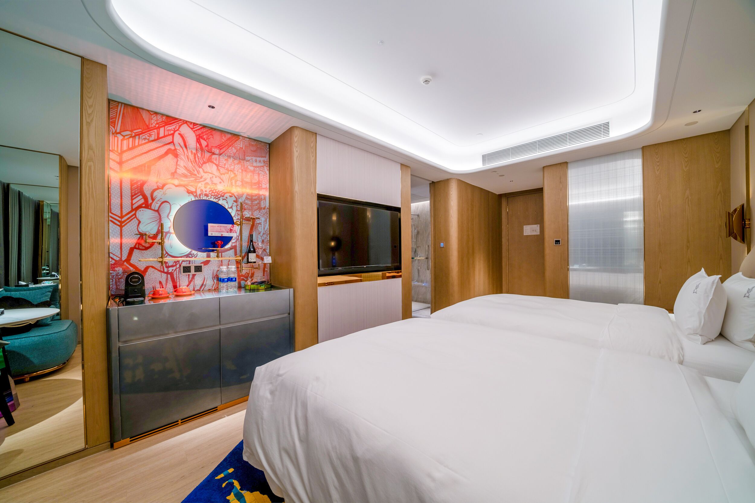 Quarto de hotel moderno com uma cama grande, televisão, minibar e banheiro com chuveiro.