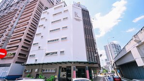 Um hotel de vários andares com entrada imponente, uma bandeira e uma placa indicando que se trata de um hotel.