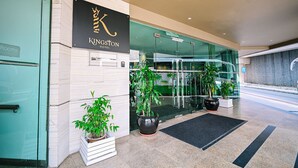 Entrada de um hotel com uma placa indicando 'KINGSTON HOTEL' e um balcão de recepção.