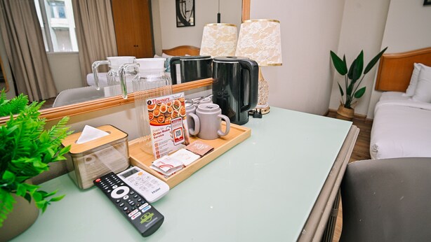 Quarto de hotel com cama, mesa com cafeteira, controle remoto e bandeja com menu.