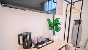 Uma cozinha compacta com cafeteira, xícaras de chá e uma bandeja com sachês de chá.