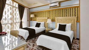 Quarto de hotel com duas camas, uma mesa e uma cadeira.