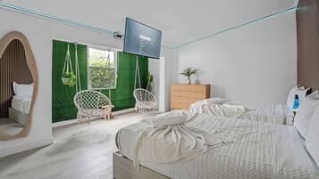 Quarto moderno com cama, duas cadeiras penduradas, uma TV e um armário de madeira.