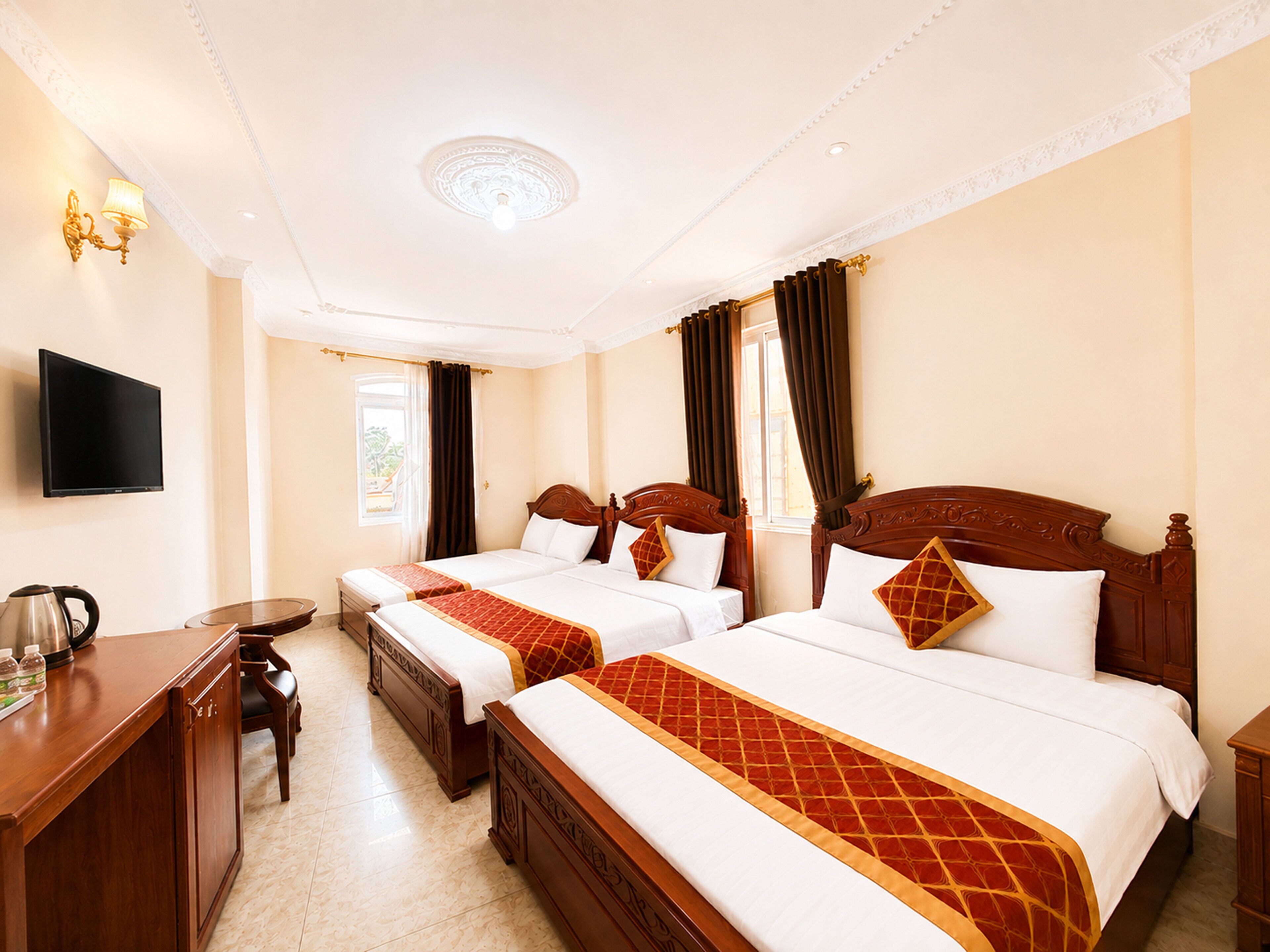Quarto de hotel com duas camas, televisão de tela plana, escrivaninha com chaleira e janela com cortinas.