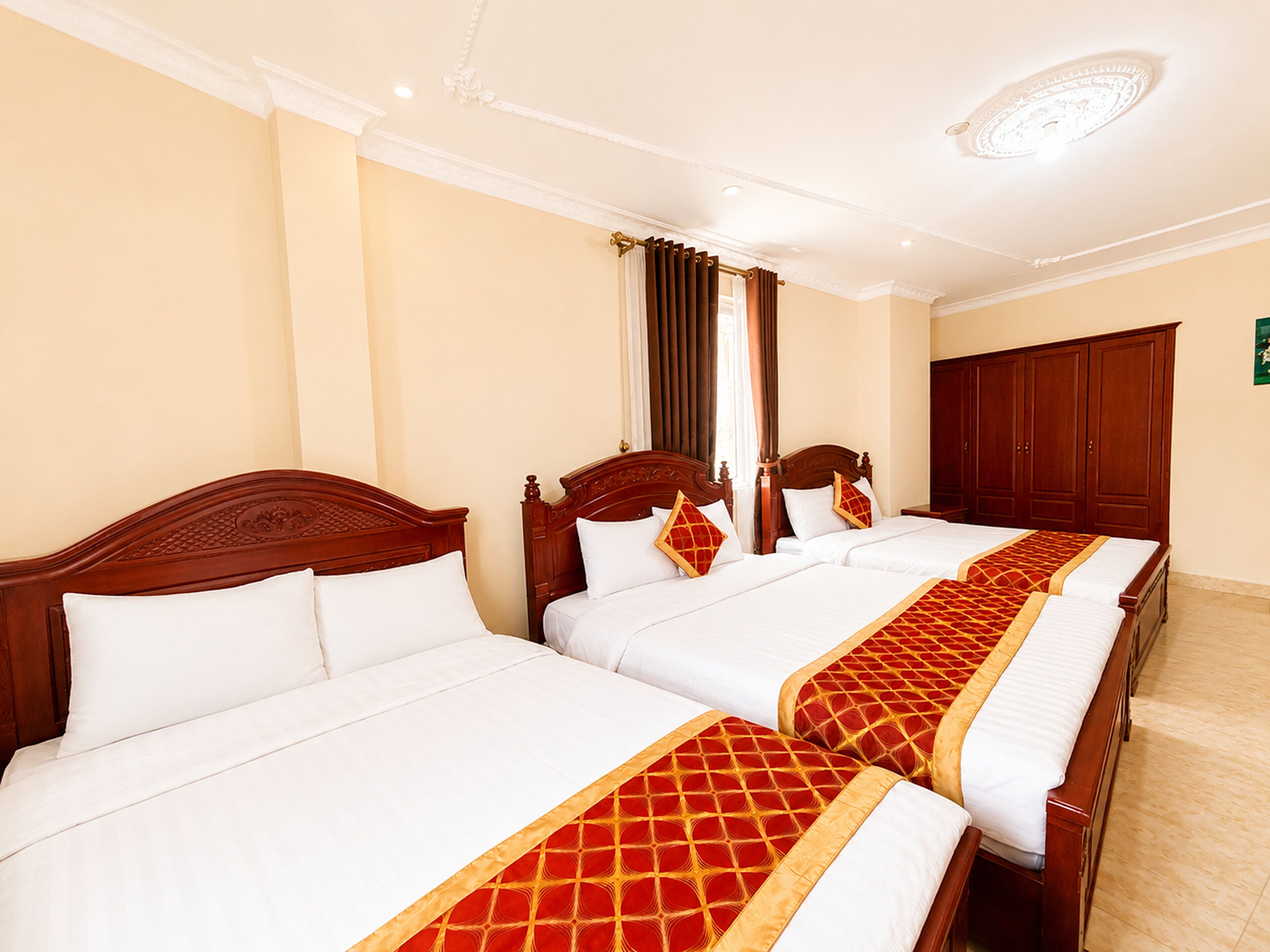 Quarto de hotel com três camas de casal, um guarda-roupa e uma janela grande com cortinas.