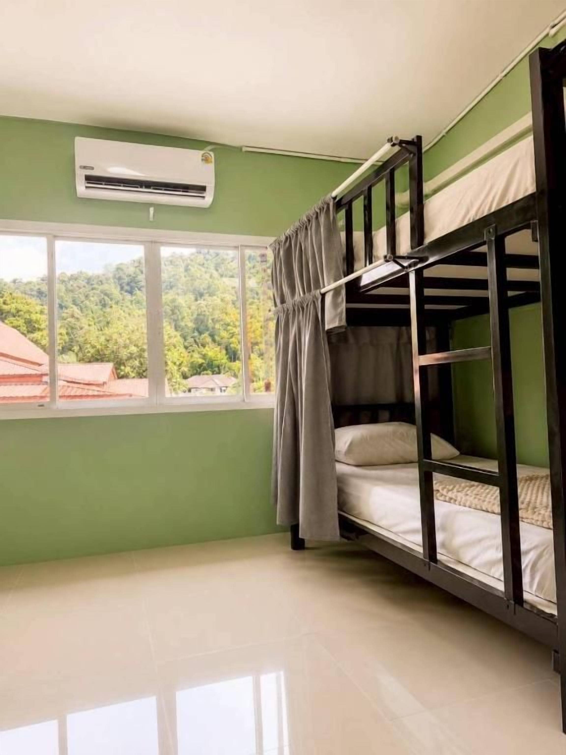 Quarto com beliche, ar condicionado e vista para o verde lá fora.