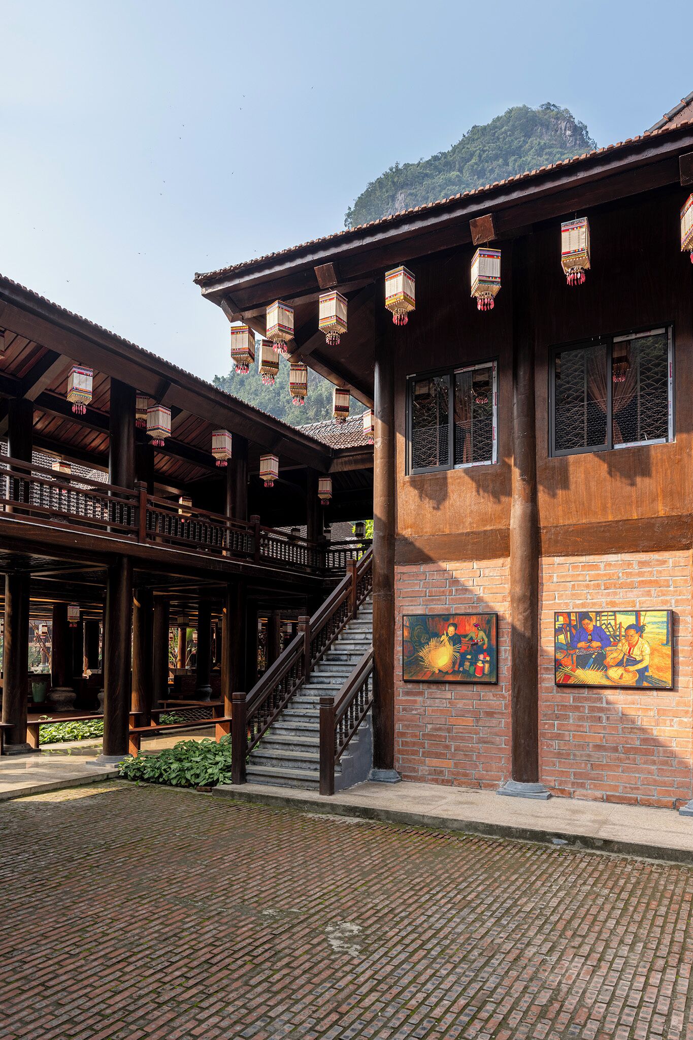 Um edifício tradicional com escadaria de madeira, paredes de tijolo e lanternas penduradas.