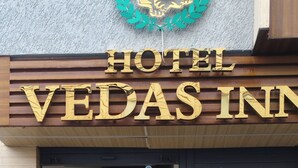 Entrada de um hotel com uma placa indicando 'HOTEL VEDAS INN' e uma escadaria que leva ao interior.