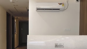 Uma área de recepção com lustre, unidade de ar condicionado e balcão de recepção com a inscrição 'Hotel Vedas Inn'.