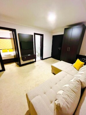 Quarto com cama, guarda-roupa, televisão e porta que dá para outro espaço.