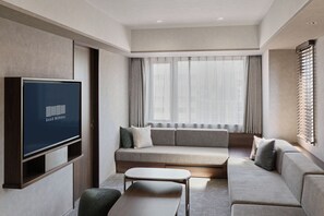 Uma sala de estar moderna com televisão de tela plana, sofá, mesa de centro e janela com cortinas.