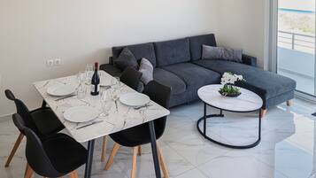 Um espaço de estar moderno com área de jantar, um sofá cinza e uma pequena mesa redonda com uma planta.