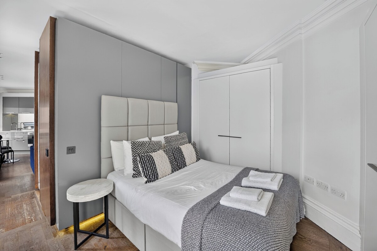 Quarto moderno com uma cama grande, mesa de cabeceira e guarda-roupa.