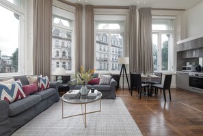 Uma sala de estar moderna com um sofá cinzento, uma mesa de centro e uma área de jantar com cadeiras e mesa.